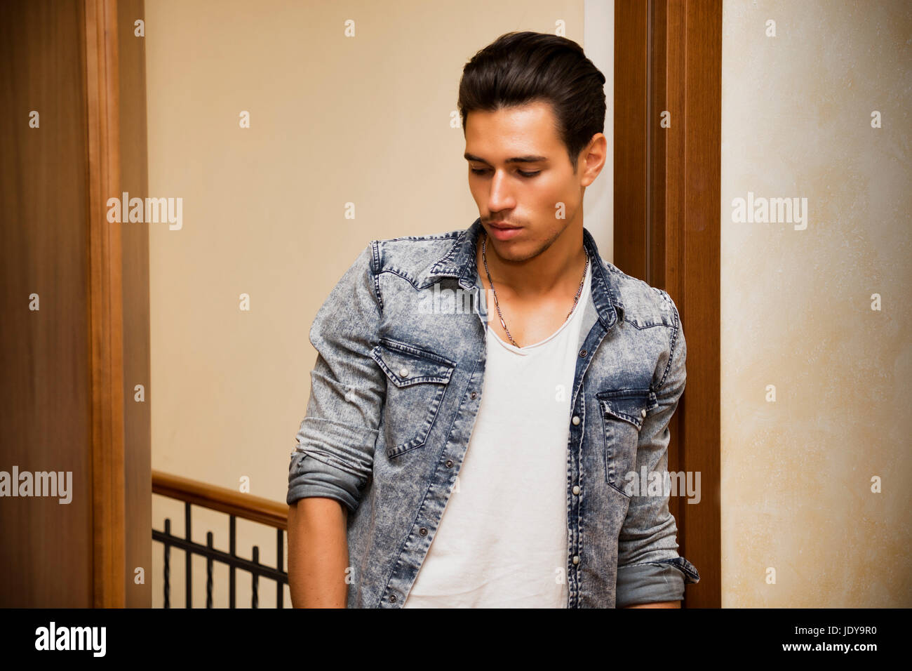 Attractive young man indoors, leaning against door jamb Stock Photo - Alamy