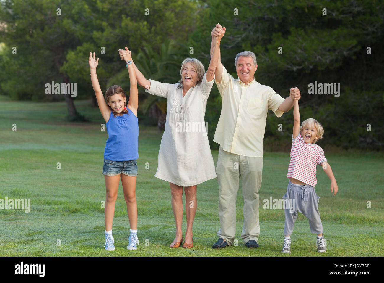 Smiling grandparents standing with their grandchildren cheering in the ...