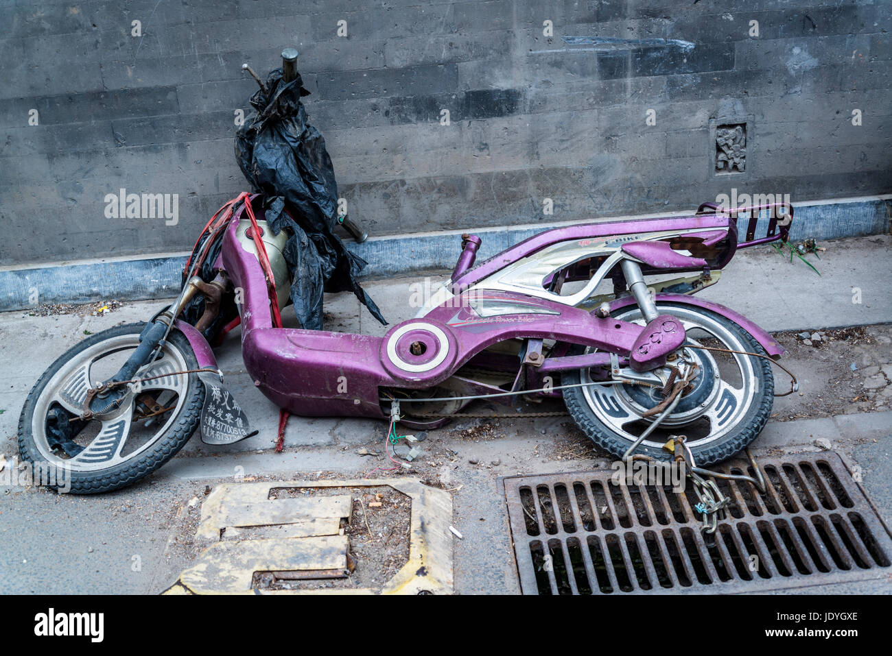 Broken and abandoned scooter in a street in the traditional Jiugulou ...
