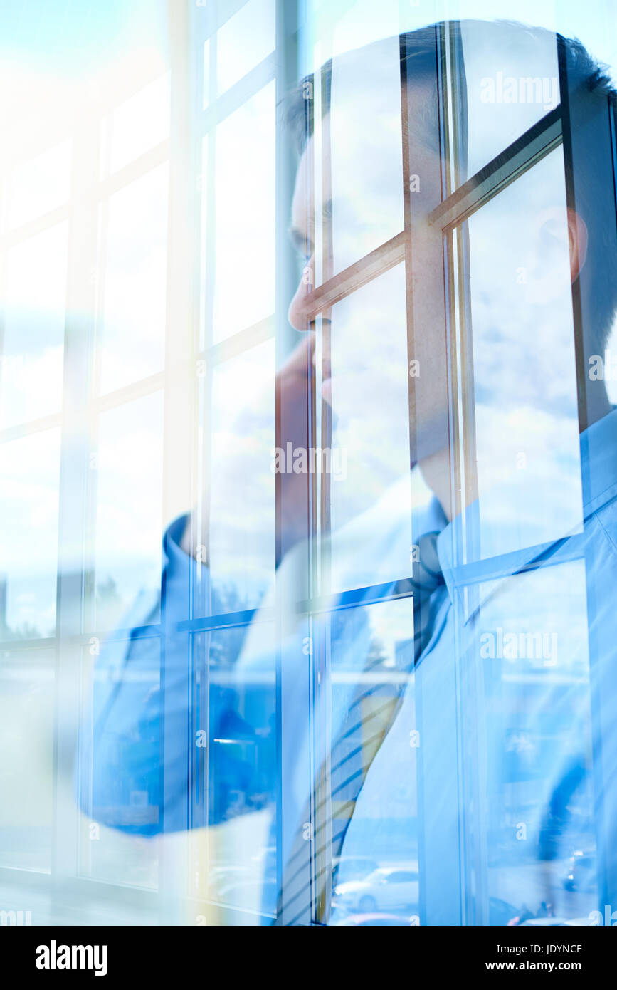 Young businessman calling in office window Stock Photo - Alamy