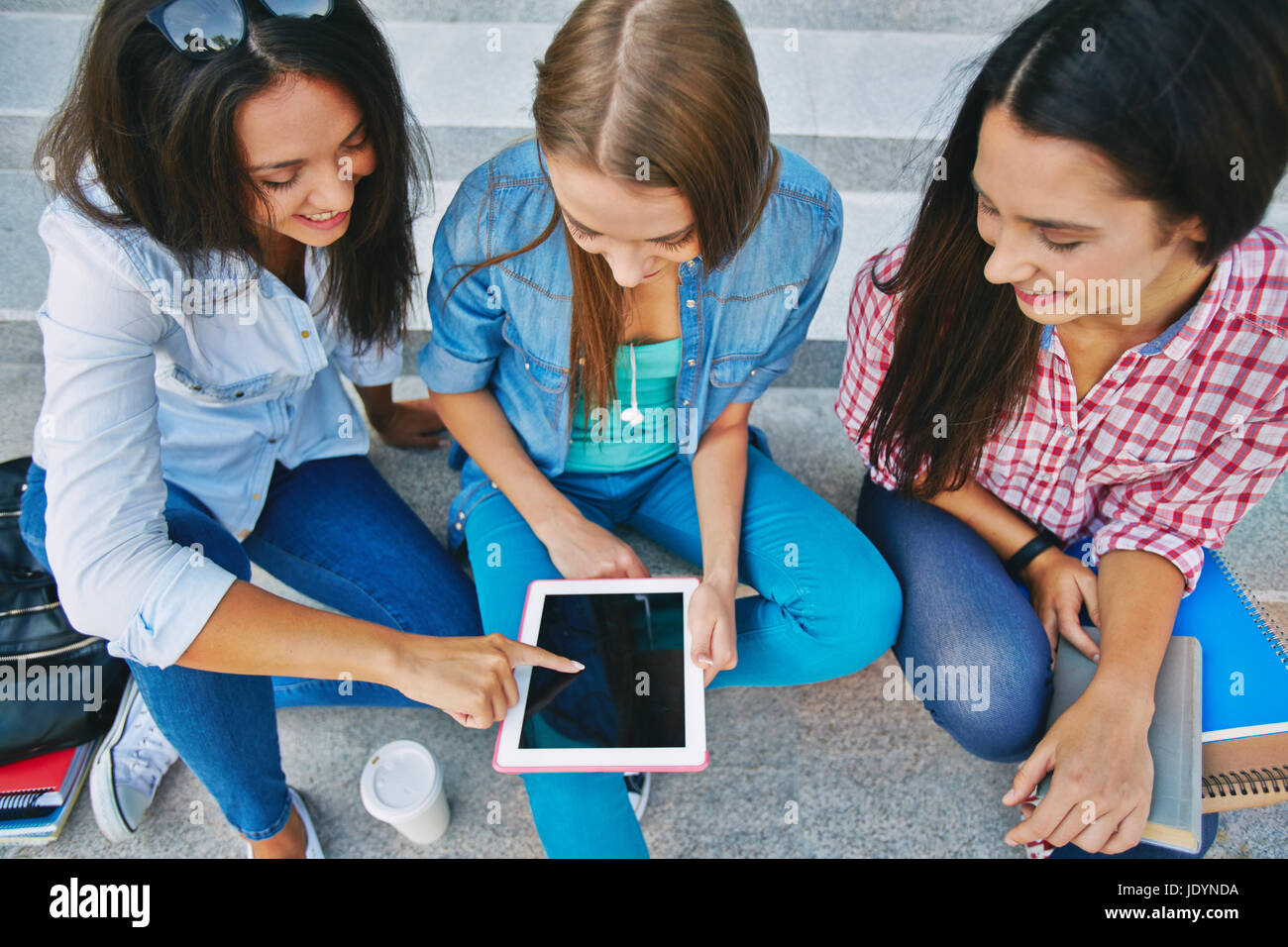 Modern teen girls using touchpad while sitting on stairs Stock Photo ...
