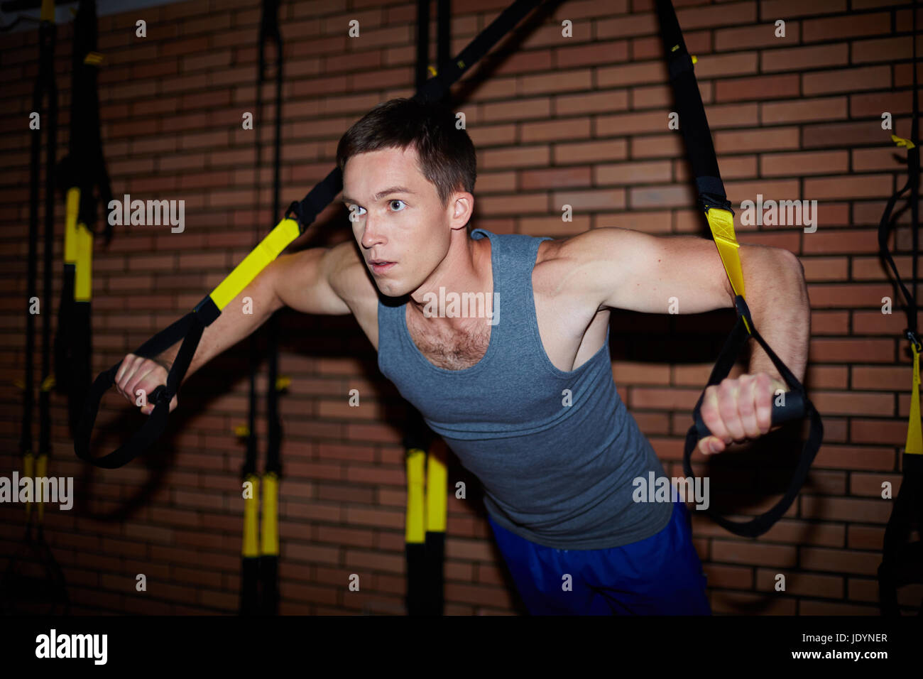 Young man doing exercises for arm muscles in gym Stock Photo - Alamy