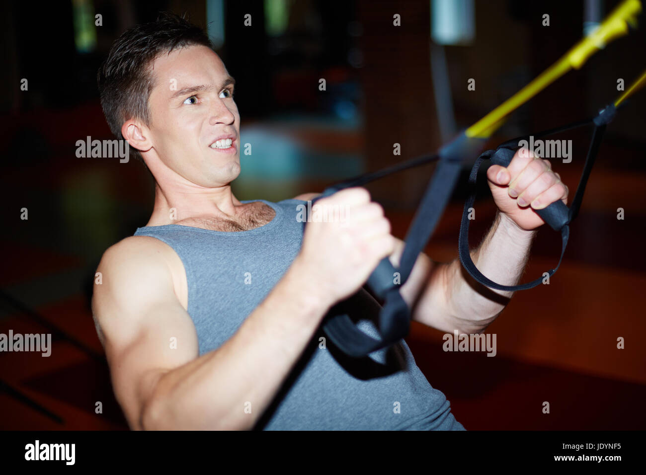 Young man making great effort while doing difficult exercise in sports ...