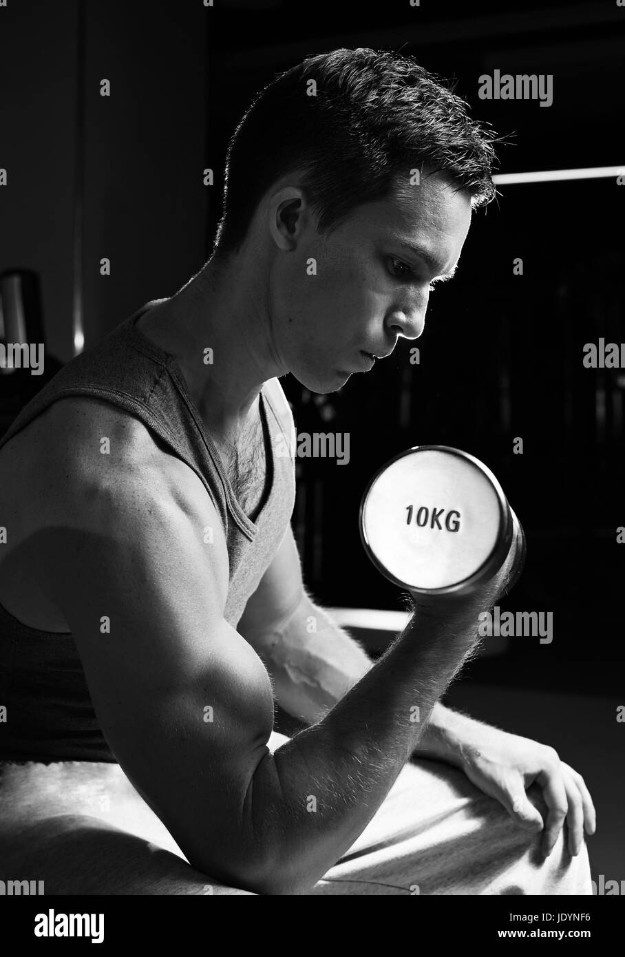 Black-and-white image of handsome man training in gym with dumbbell ...