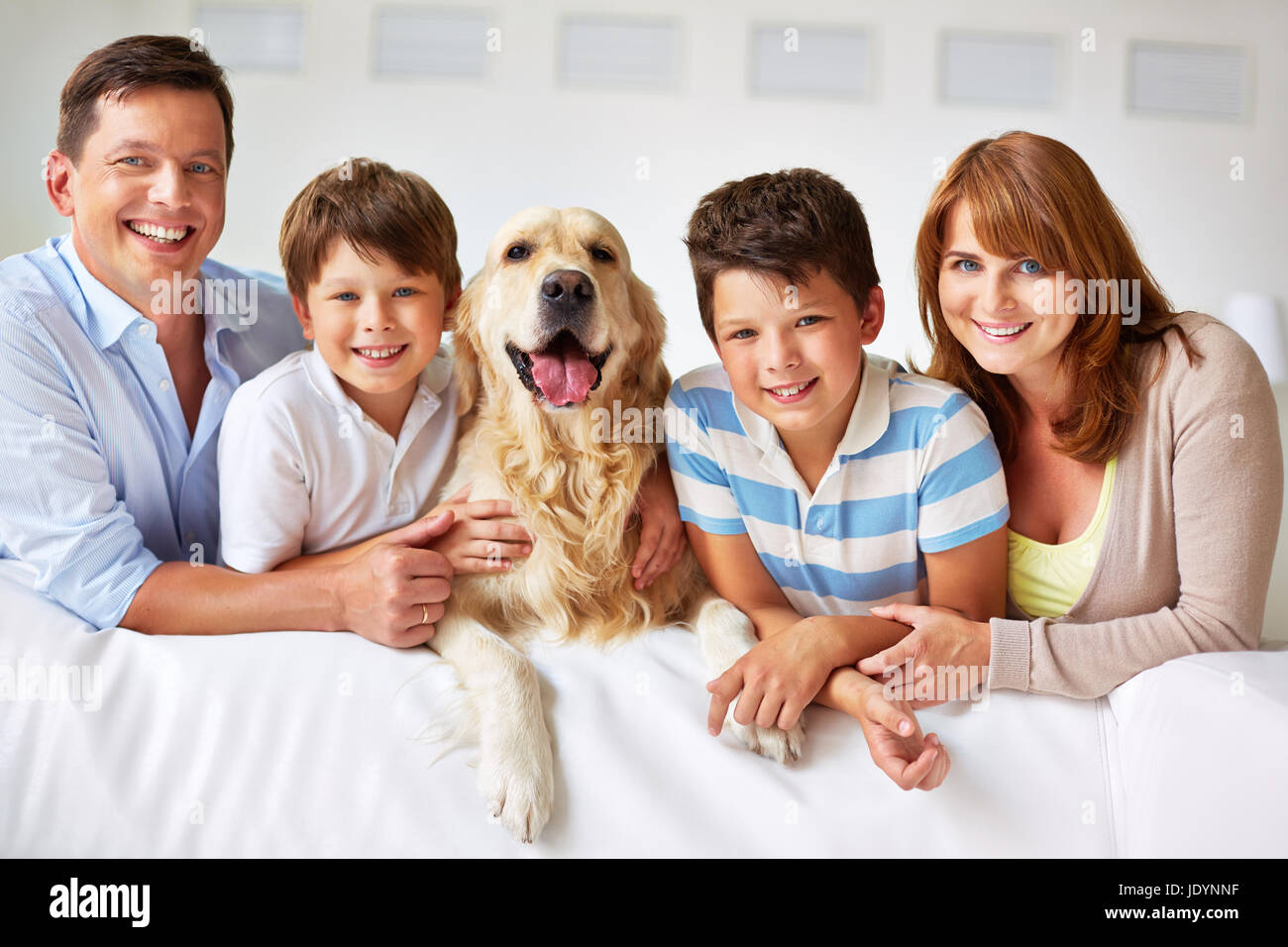 Smiling family with thoroughbred dog looking at camera Stock Photo - Alamy