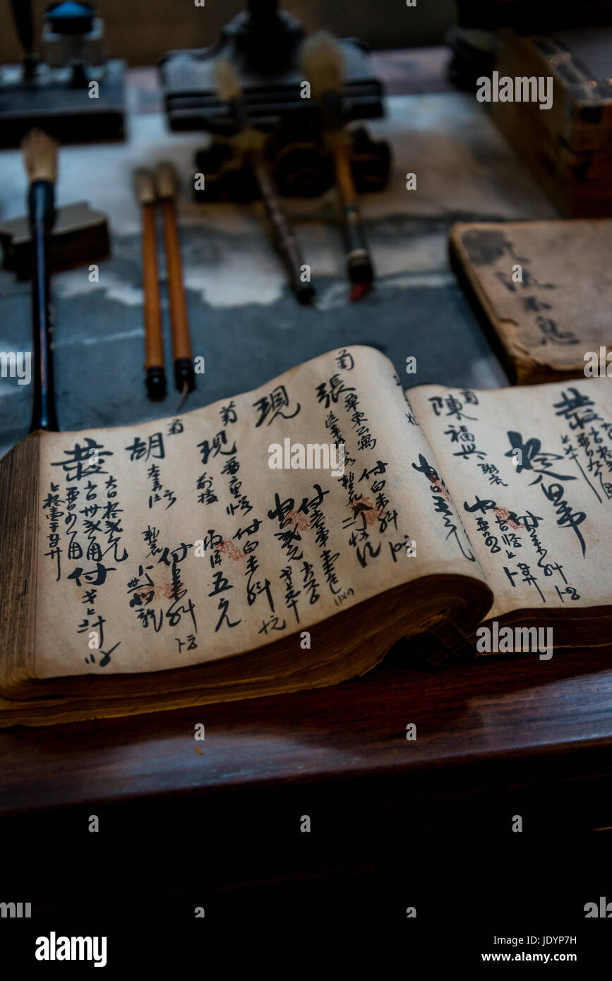 Traditional writer's desk with an open book with Chinese brush and ink ...