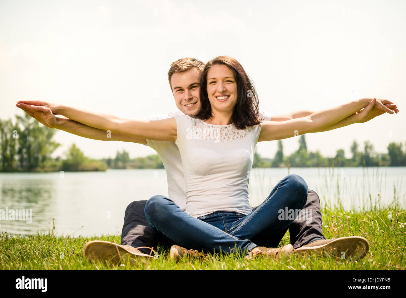 Young couple enjoy life together in nature - making airplane with hands ...