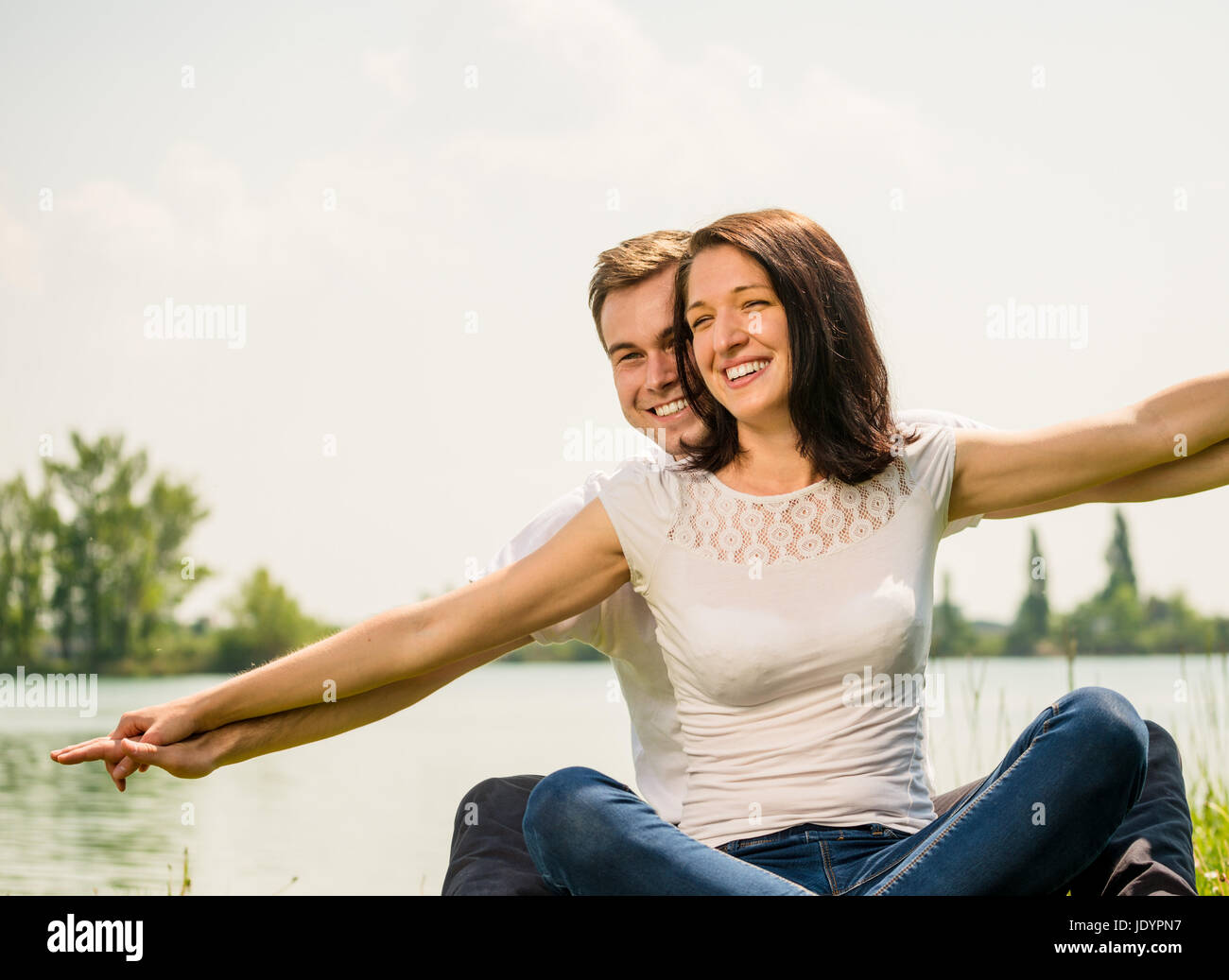 Young couple enjoy life together in nature - making airplane with hands ...