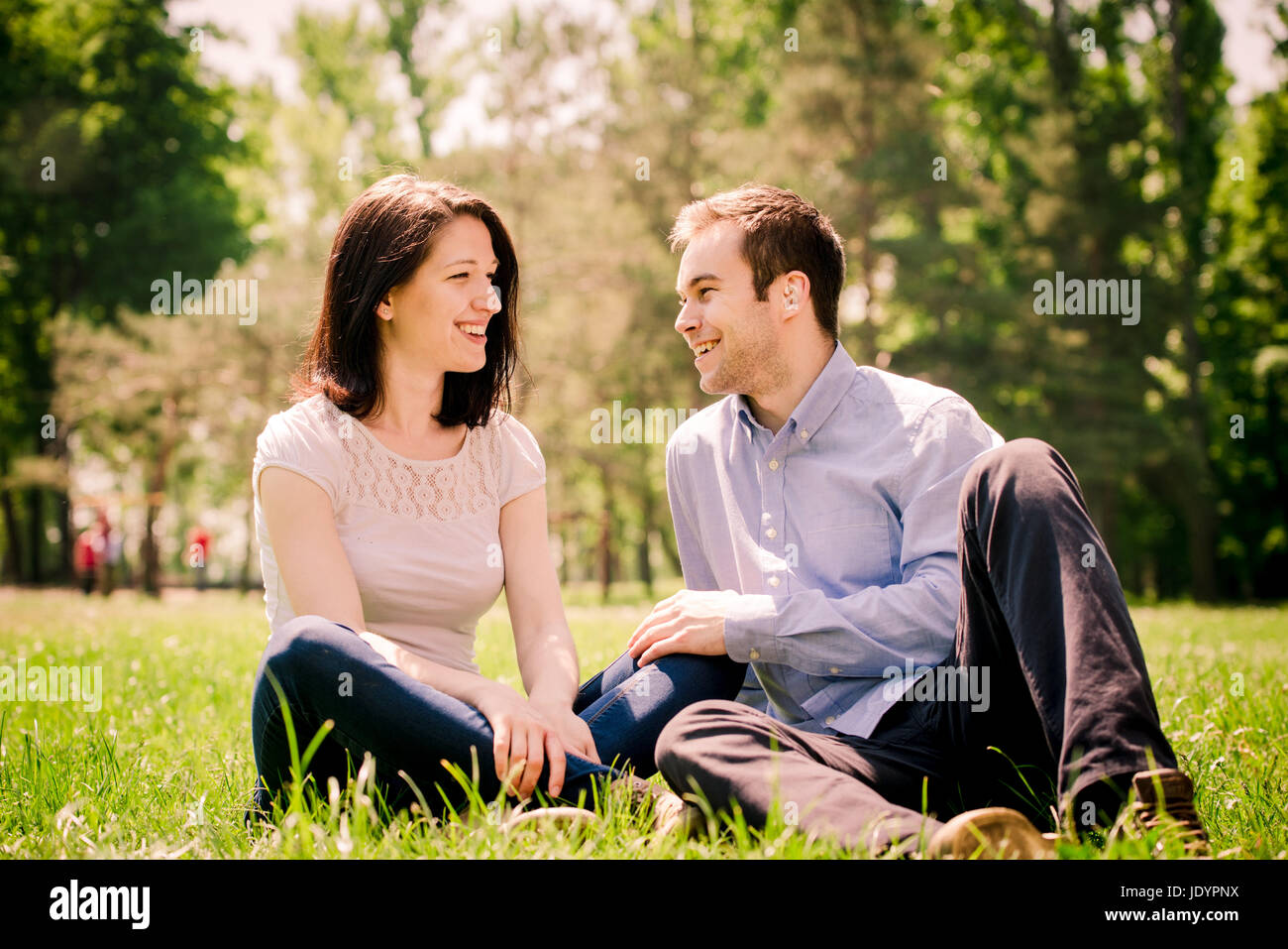 Young happy couple talking together outdoor - sitting on grass in ...