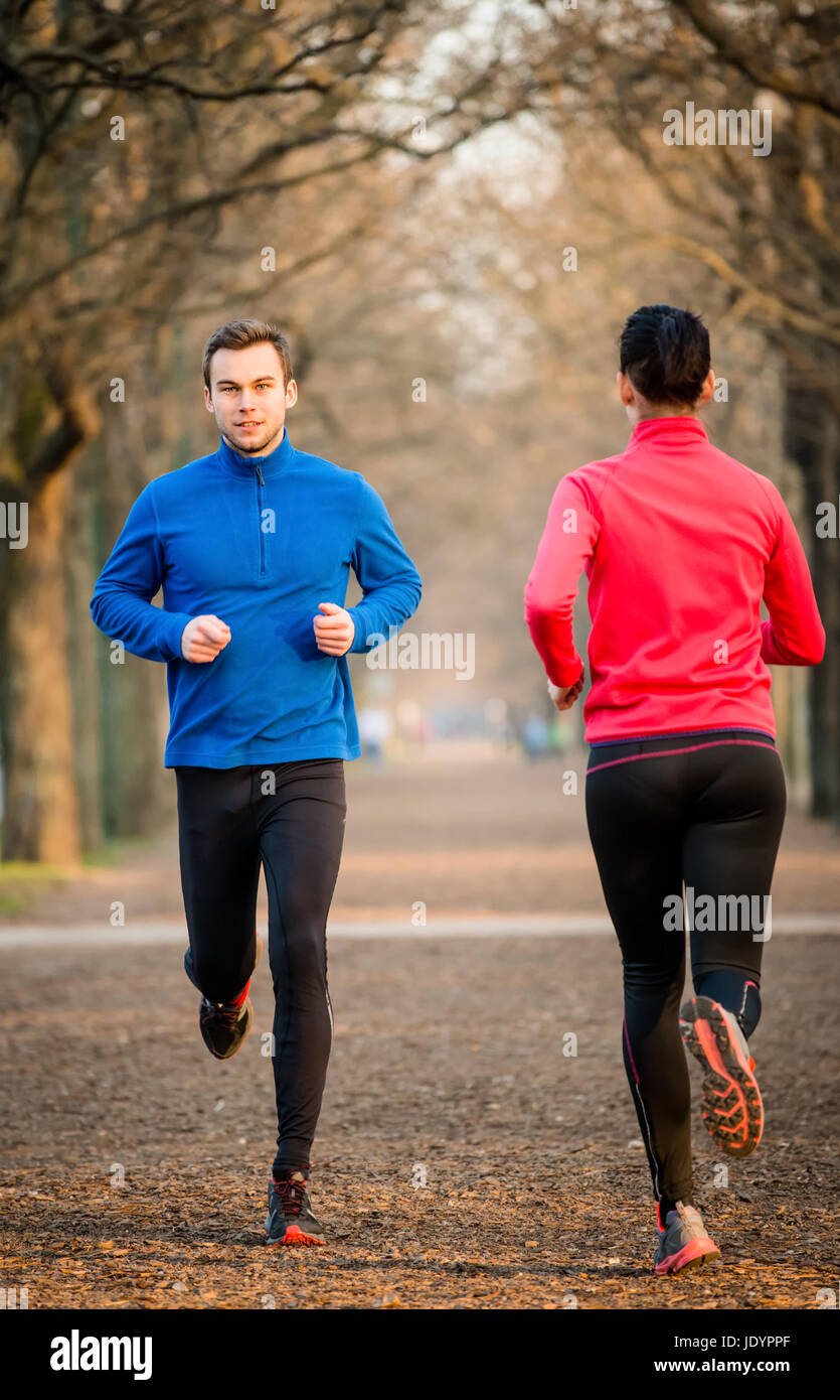 Young man jogging in park, woman running in opposite direction Stock ...