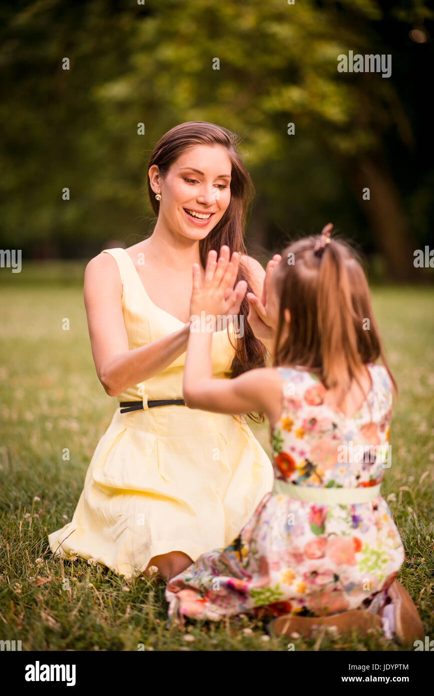 Clapping hands - mother playing with her daughter outdoor in nature ...