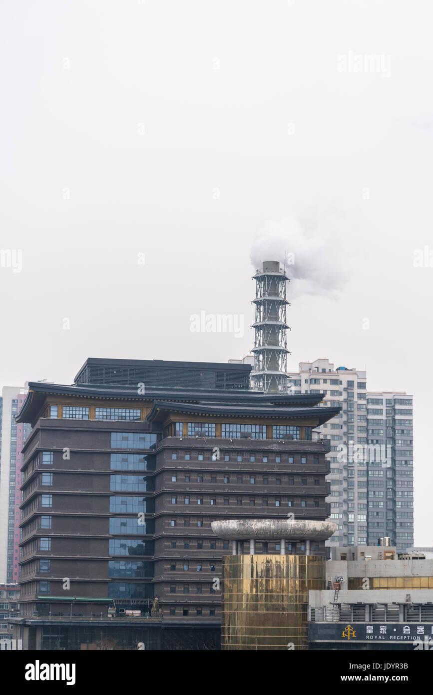 Chimney belching out smoke in the city centre surrounded by commercial ...