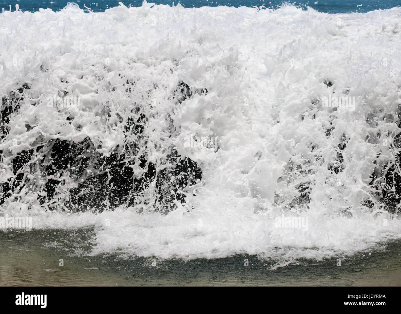 Frozen motion of ocean waterfall over rocks at Lumahai Beach Stock ...