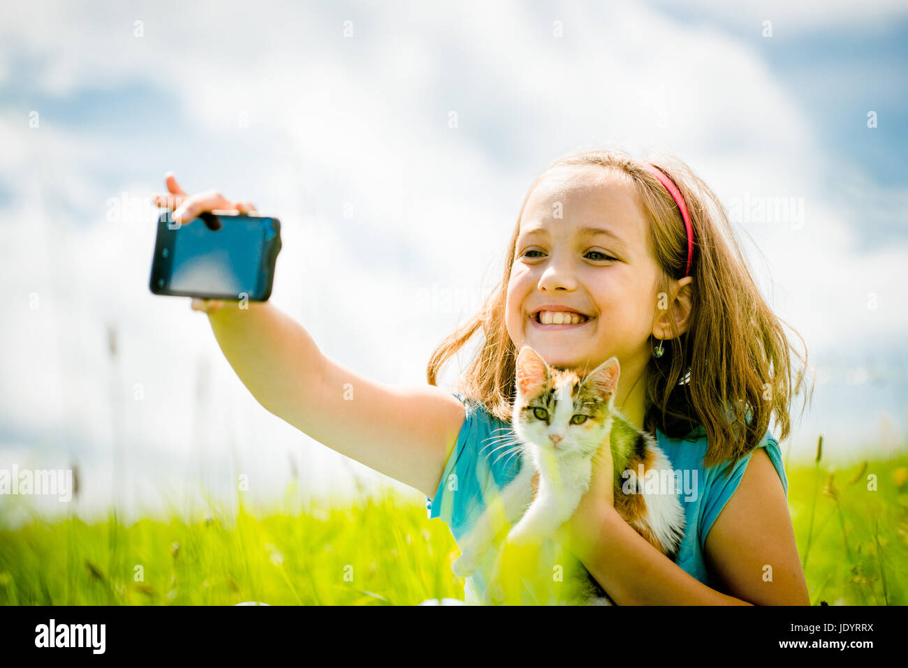 Child taking photo with mobile phone camera of herself and her cat ...
