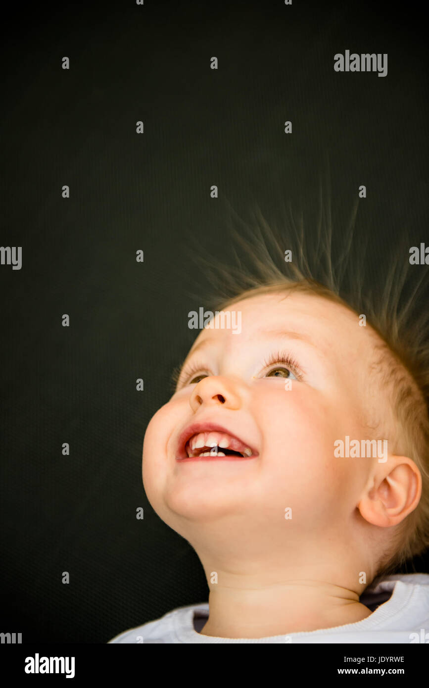 Portrait of smiling baby looking up - black background Stock Photo - Alamy