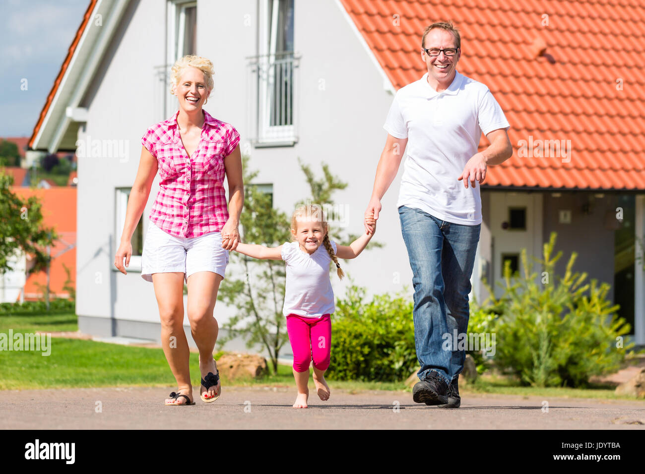 Family of Parents and child walking in front of home in village or ...