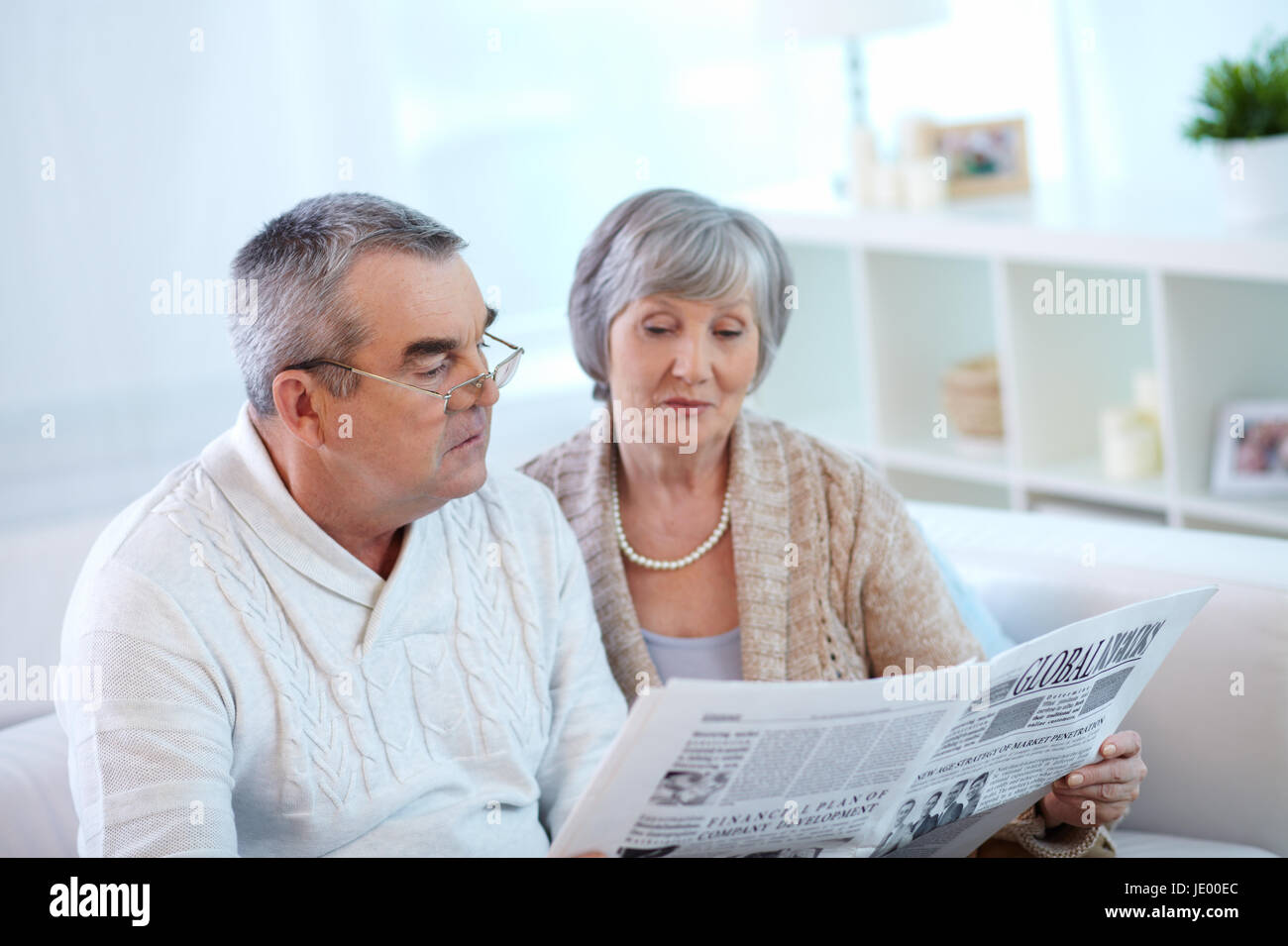 Senior couple reading newspaper together at home Stock Photo - Alamy