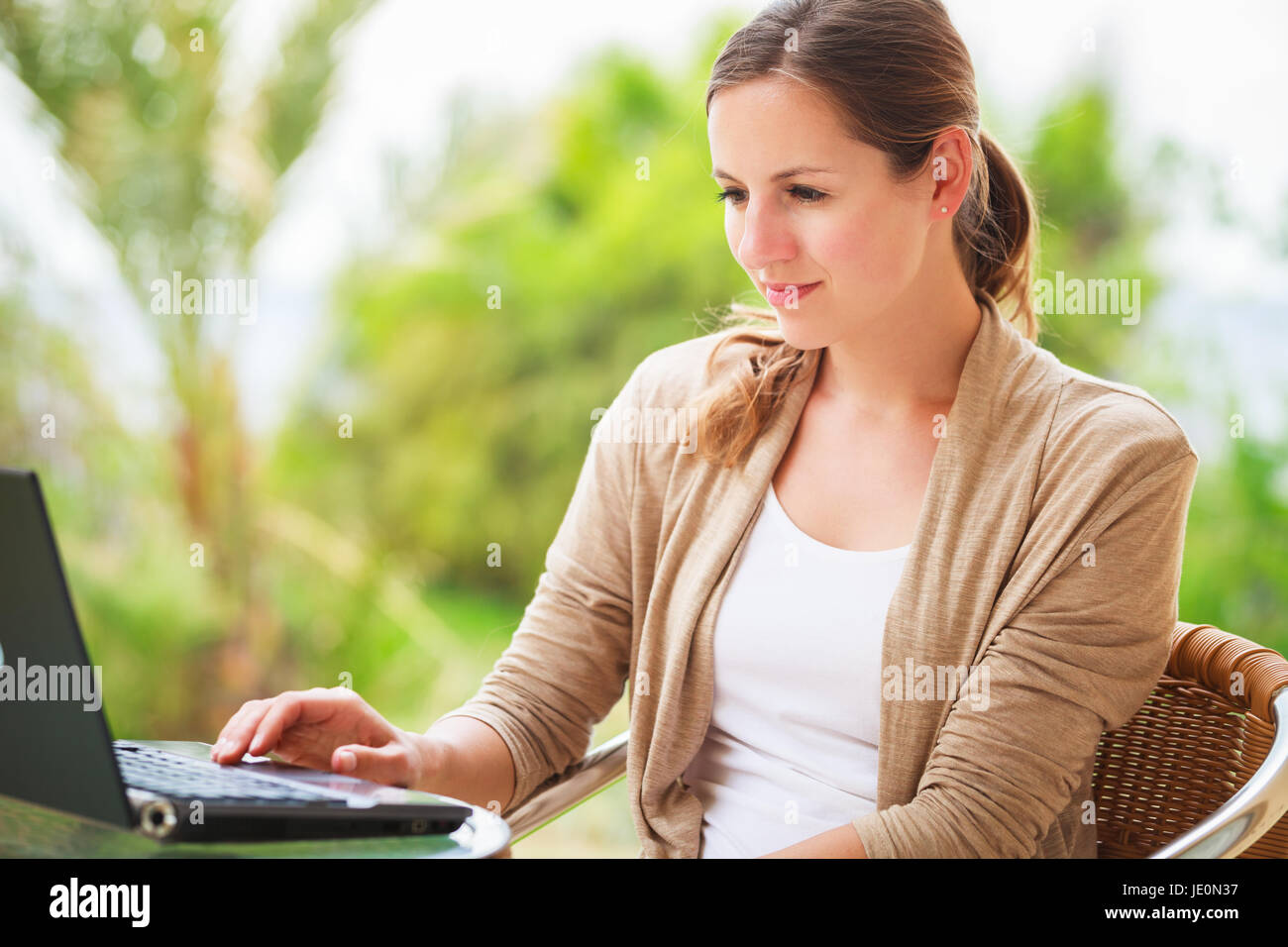Portrait of a pretty young woman working on her computer on a terrace ...