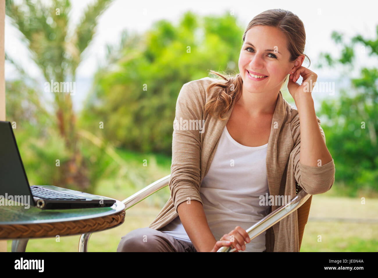 Portrait of a pretty young woman working on her computer on a terrace ...