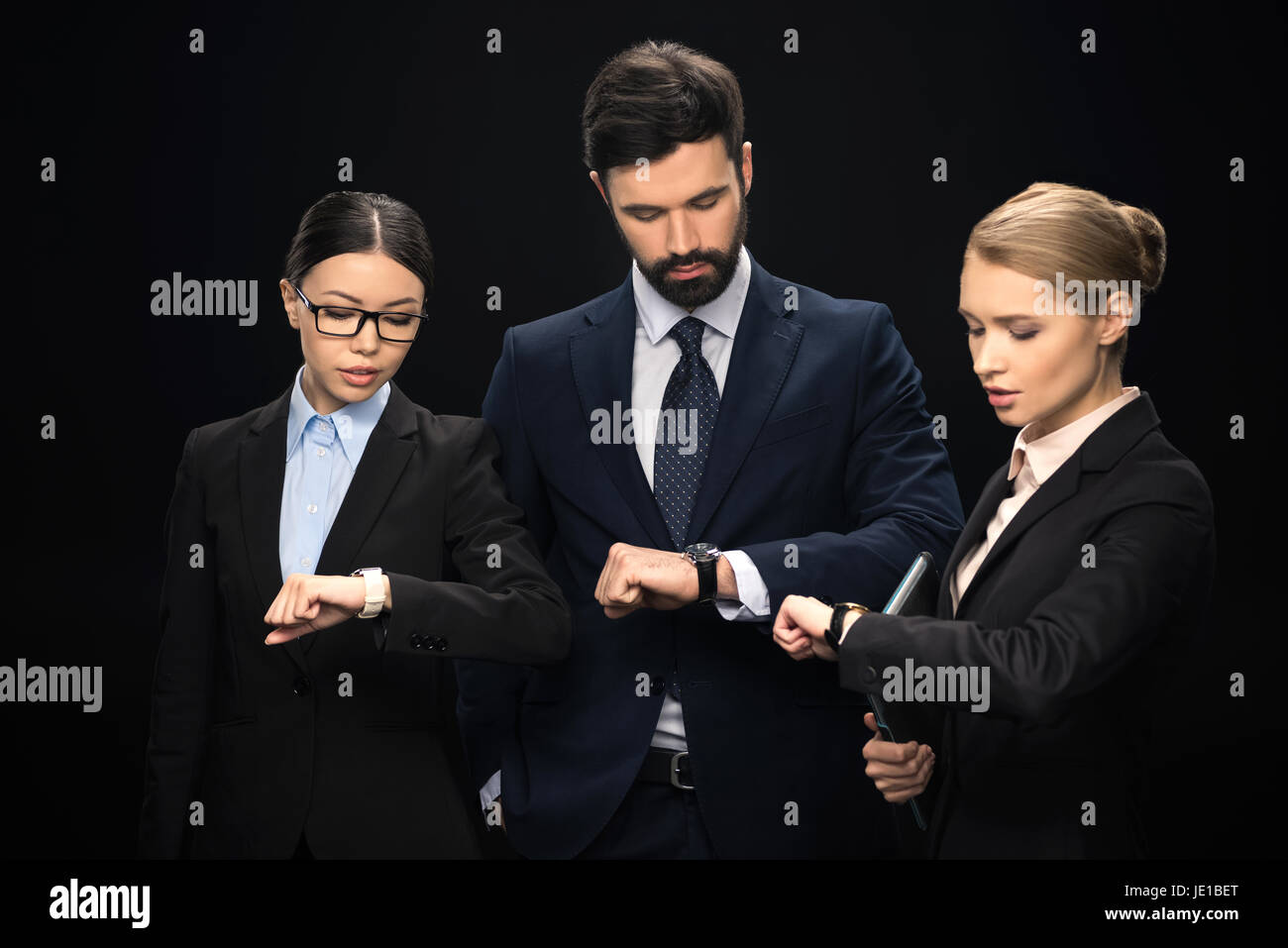 pensive business people standing and looking at watches isolated on ...