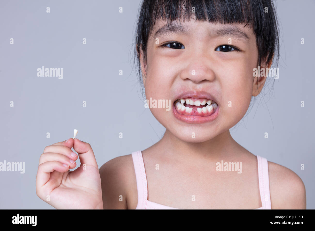 Asian Chinese little girl holding her missing tooth in isolated white ...