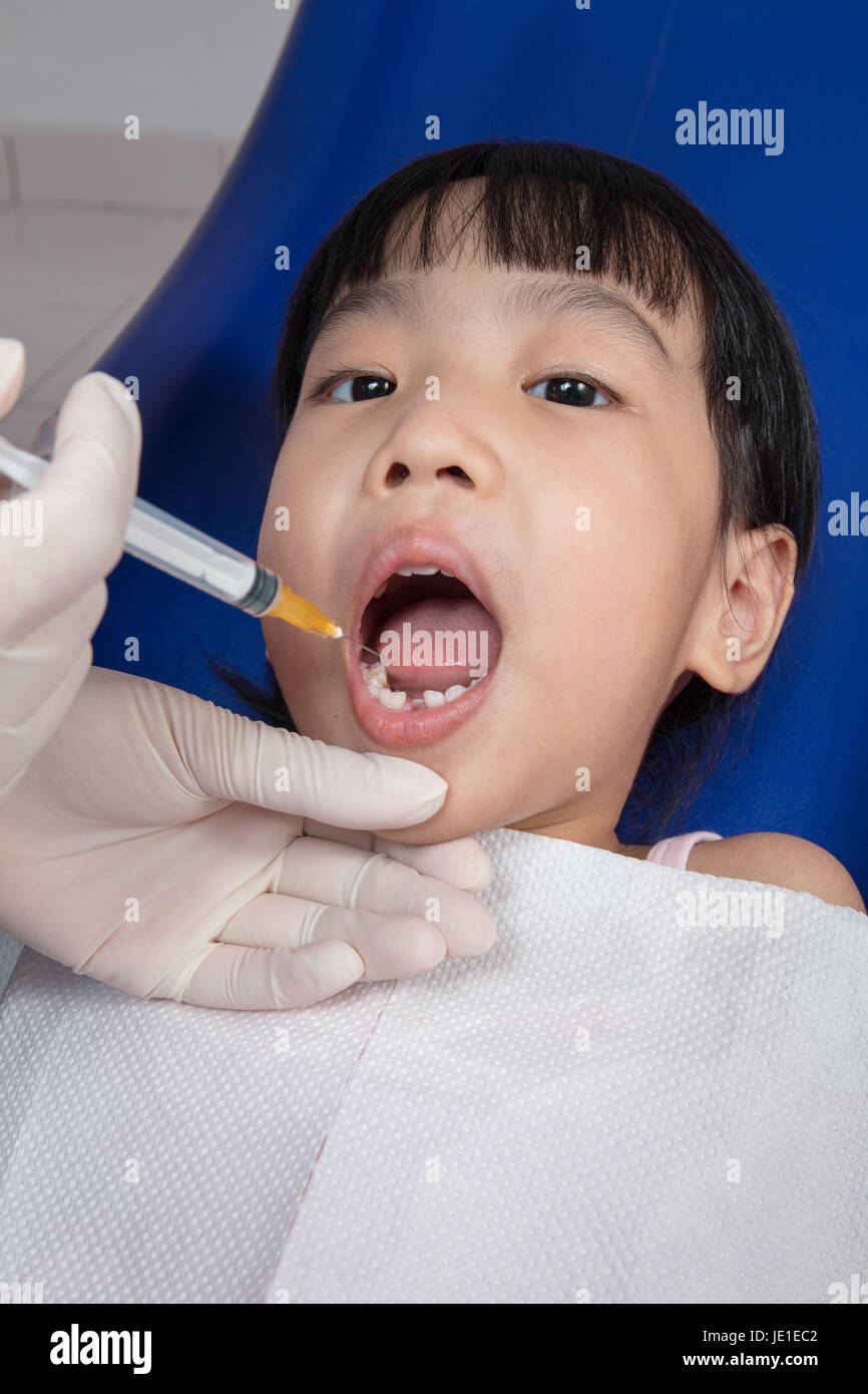 Asian Chinese little girl lying down for tooth extraction at dental ...