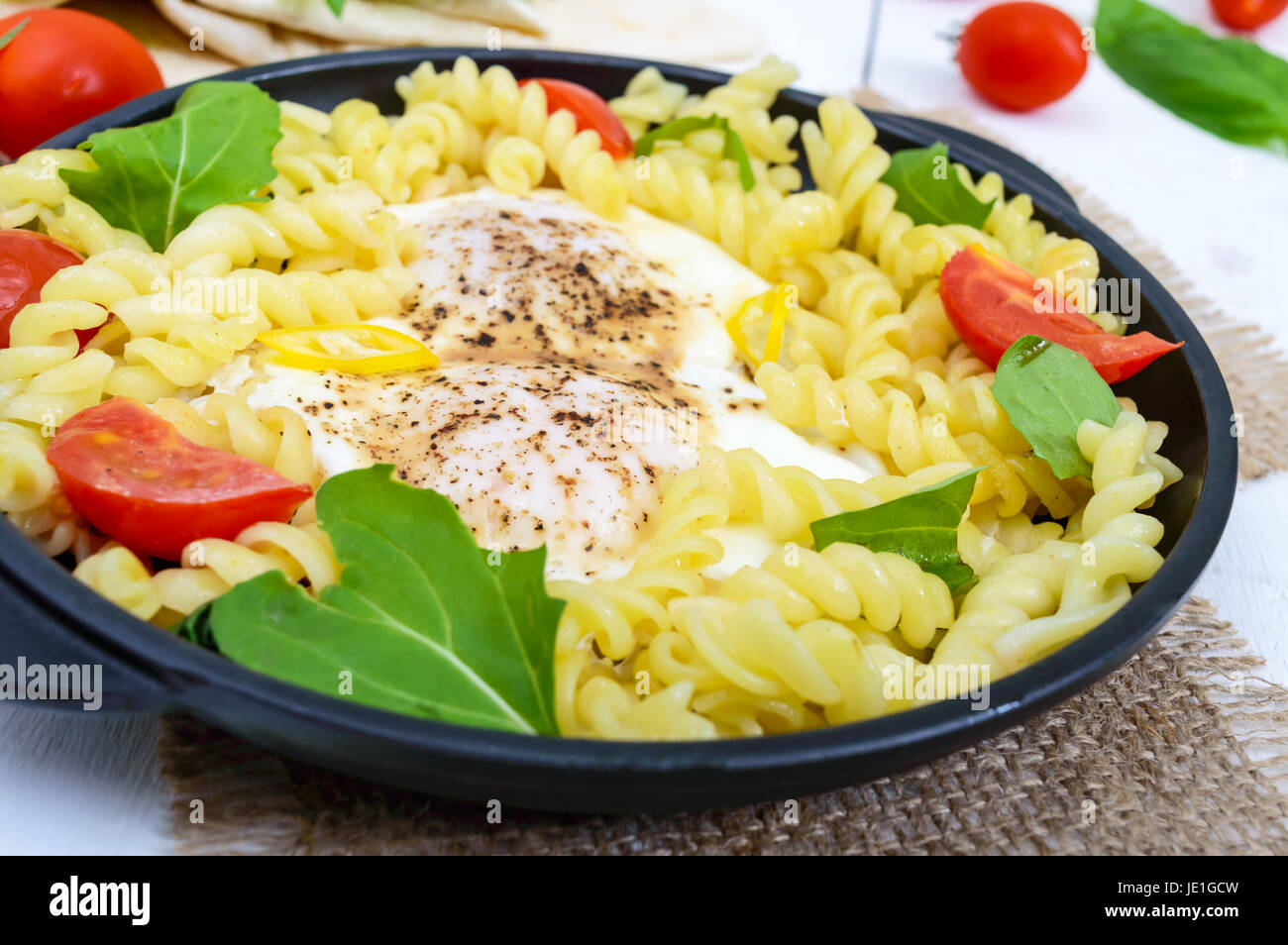 Fusilli pasta, fried eggs and tomatoes. Serve on a cast-iron frying pan ...
