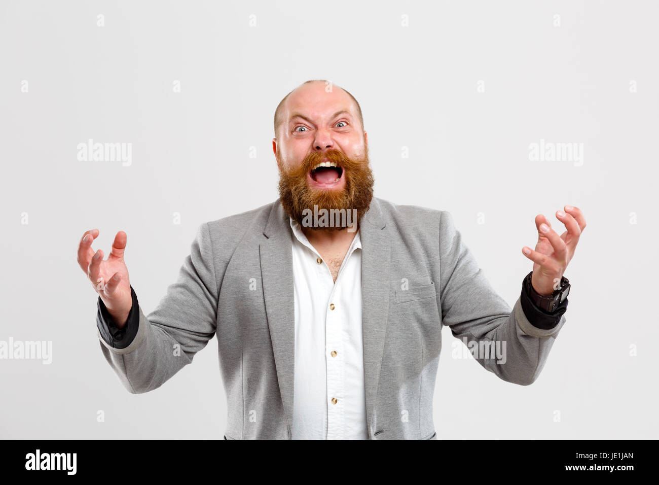 Brutal screaming man with ginger beard in gray jacket on empty ...