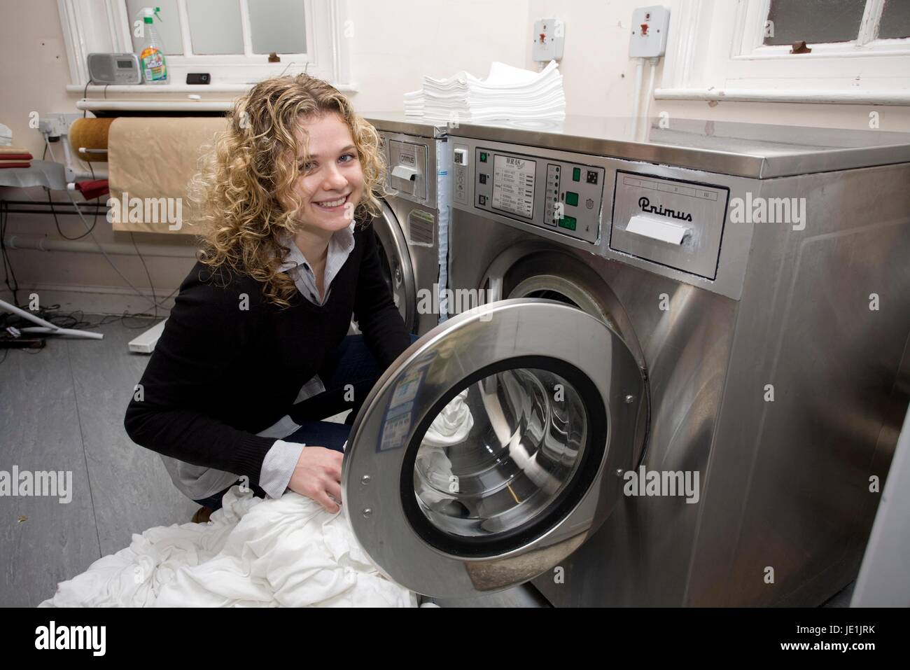 A young smiley woman filling a washing machine with dirty laundry Stock ...