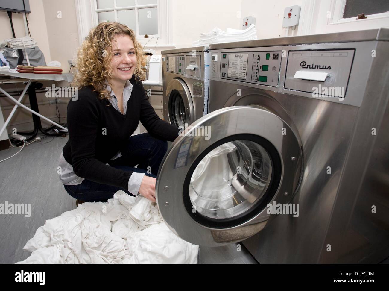 A young smiley woman filling a washing machine with dirty laundry Stock ...