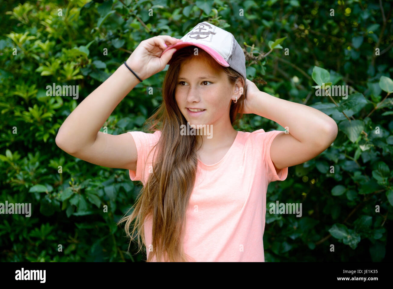 Young teenage girl with long blond hair with baseball cap. Outdoors ...