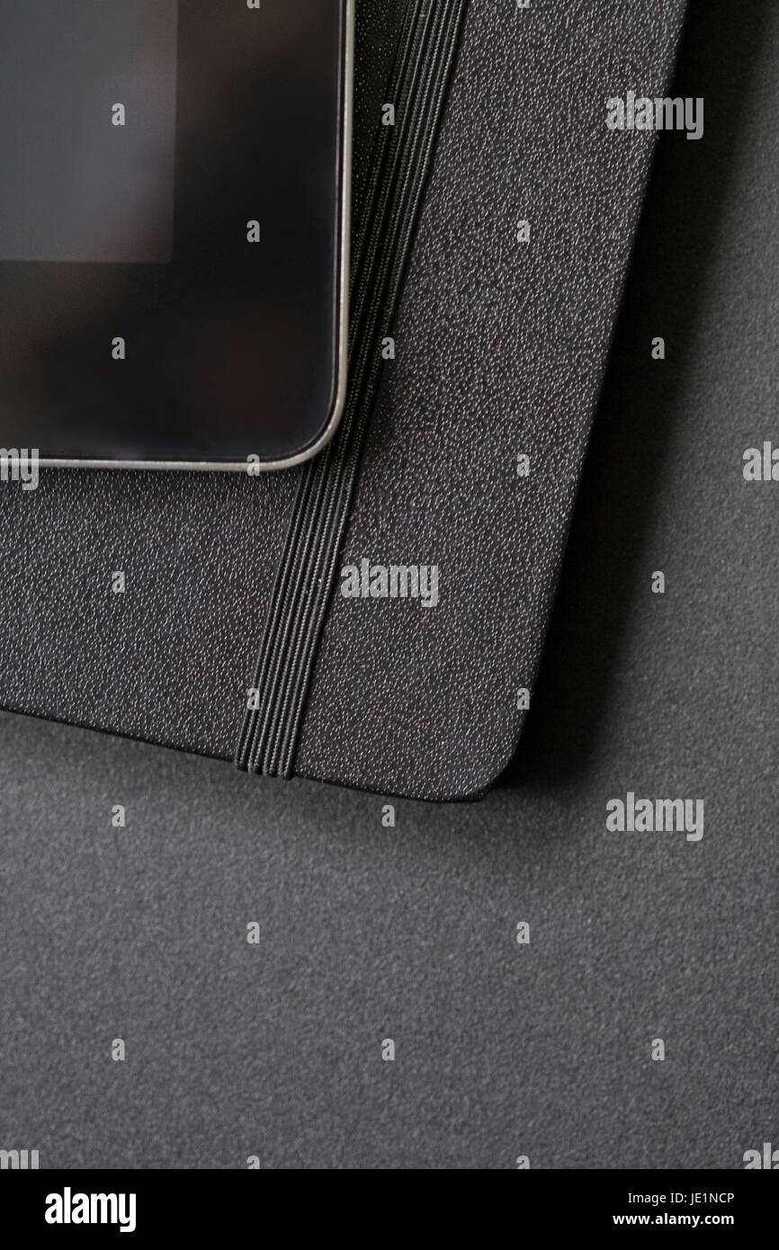 A black tablet and a black notepad on the black table Stock Photo - Alamy
