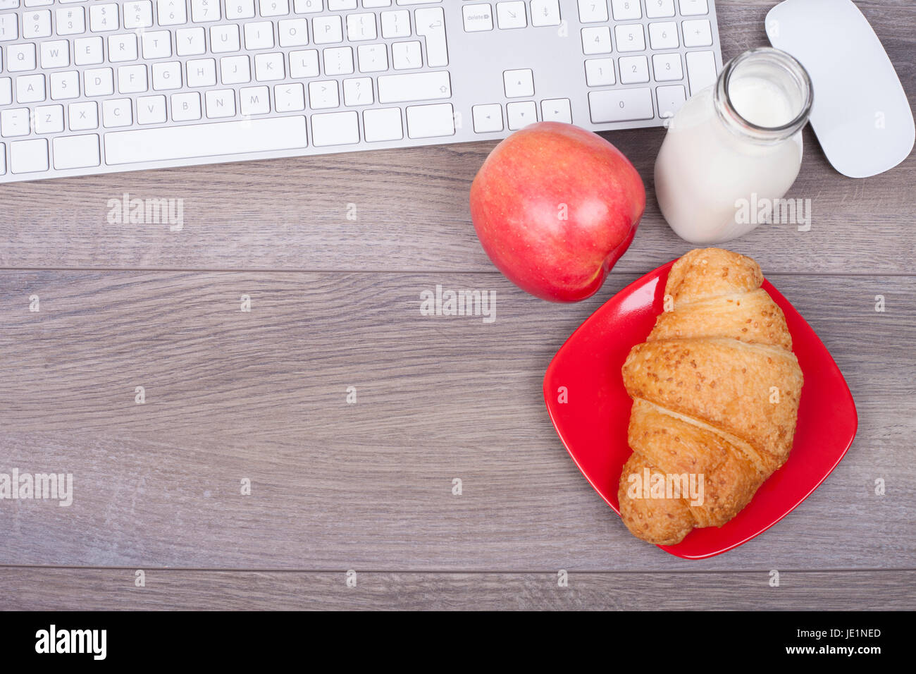 Work desk with keypad and breakfast. Keyboard on the desk, croissant ...