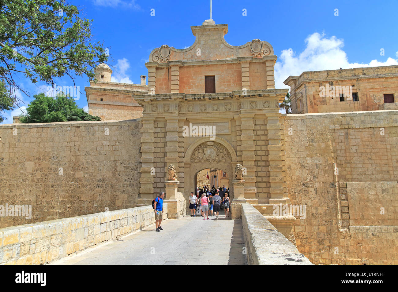 Tourists walking over moat bridge through entrance gateway of medieval ...