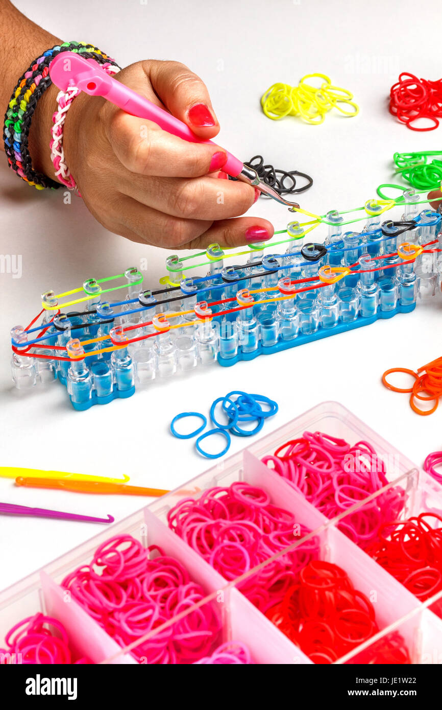 Young woman making a rubber loom bracelet with a hook Stock Photo - Alamy