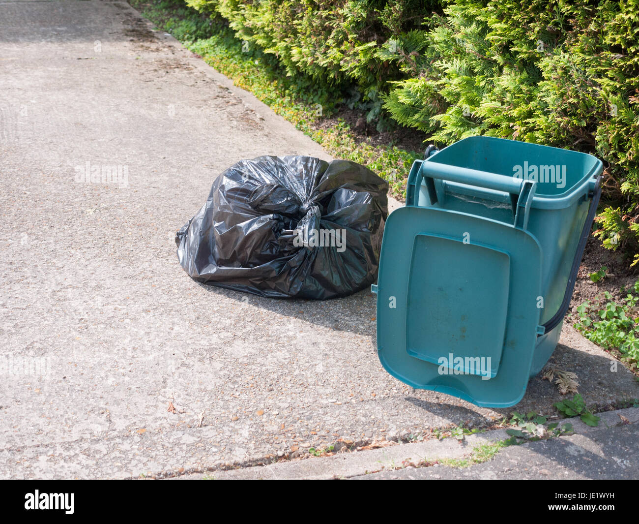 green food recycling bin open outside on front pavement with black tied ...