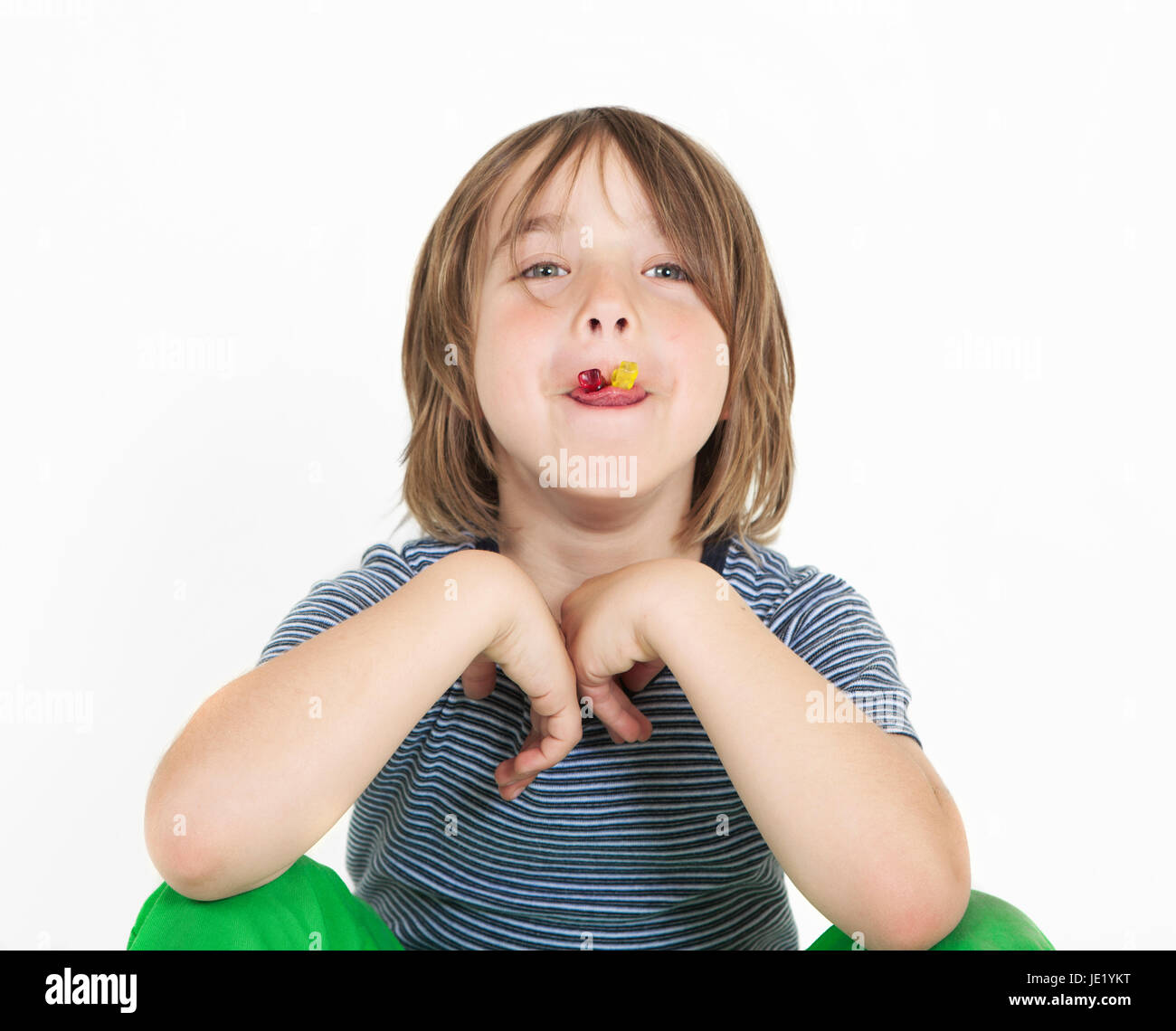 A boy with brown hair eating gummy bears, background white, isolated ...