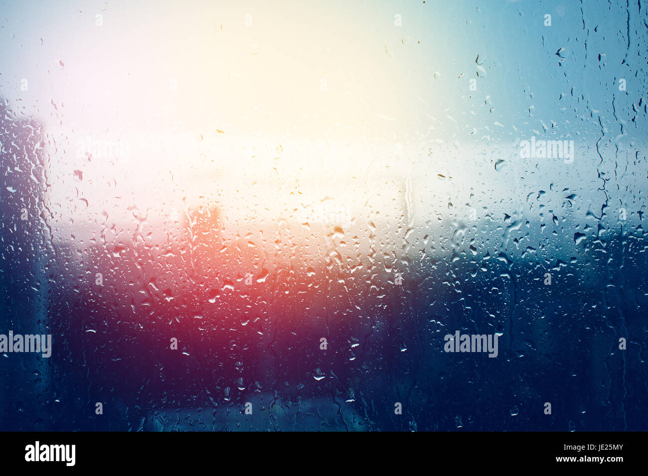 Raindrops on window glass surface, blurred city through window glass ...