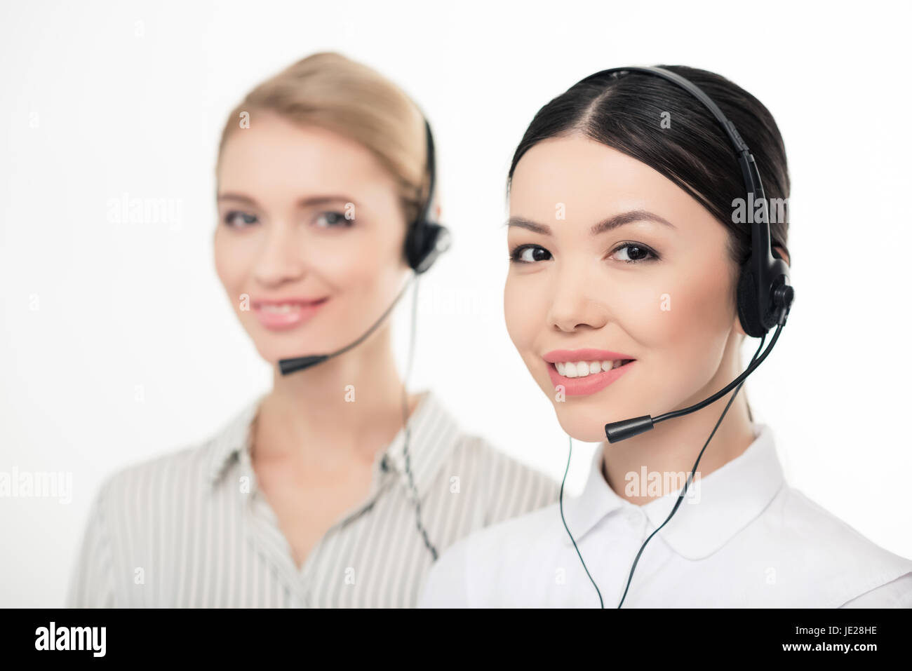 smiling call center operators in headsets isolated on white, focus on foreground Stock Photo - Alamy