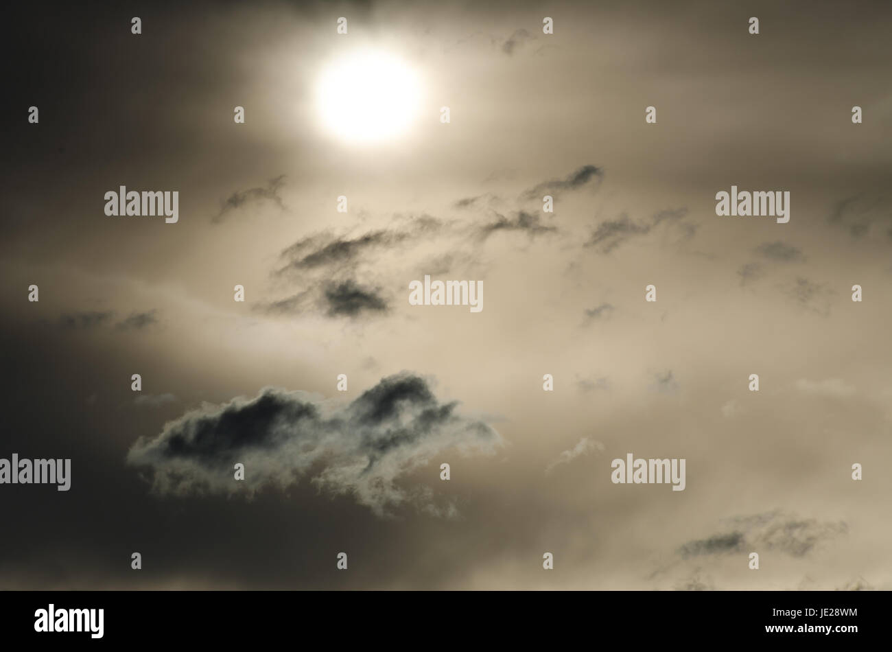 Solitary Puffs of Cloud Floating Past The Setting Sun Stock Photo - Alamy