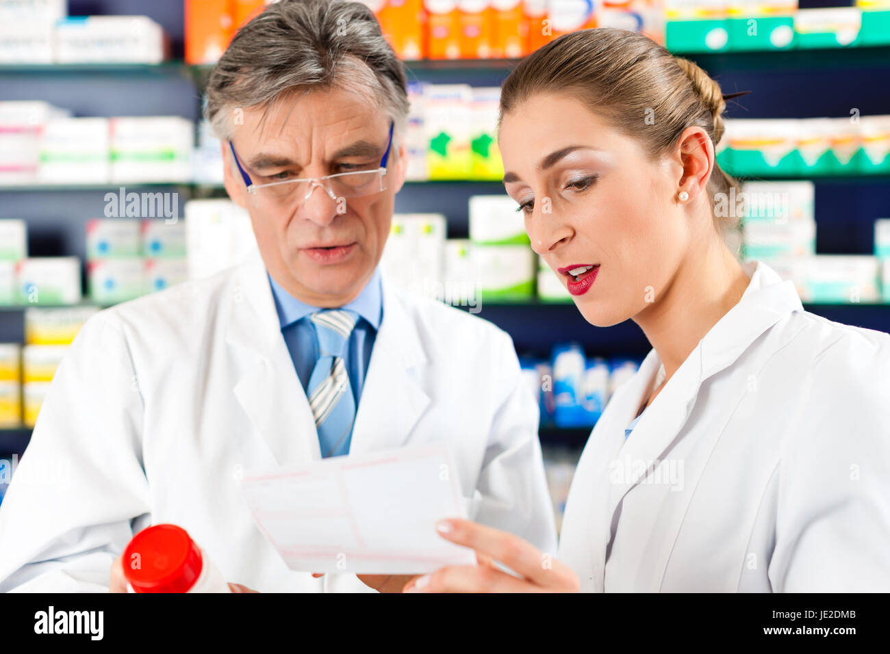 Two pharmacists with pharmaceuticals in hand consulting each other in a ...