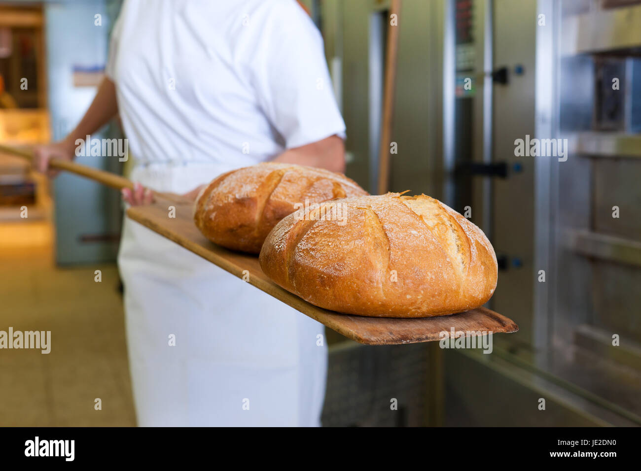 baker baking fresh bread in the bakery showing it on the shovel Stock ...