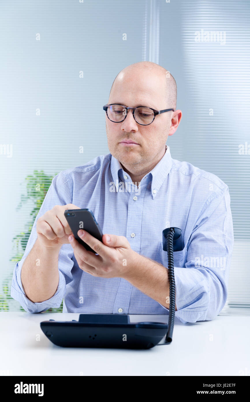 upset upright bald clerk with sunglasses dialing a number on his mobile ...