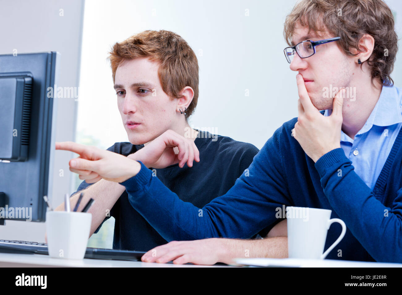 a couple of young employees in an office working together to achieve ...