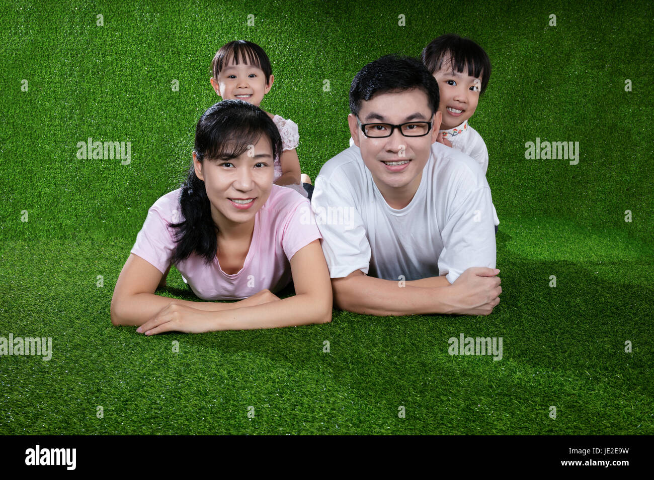 Happy Asian Chinese parents and daughters lying on the grass at outdoor ...