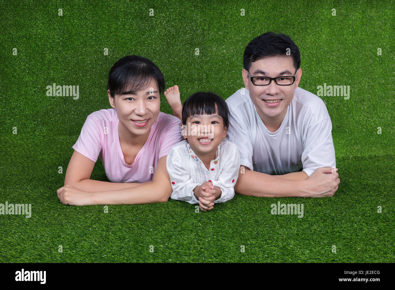 Happy Asian Chinese parents and daughter lying on the grass at outdoor ...