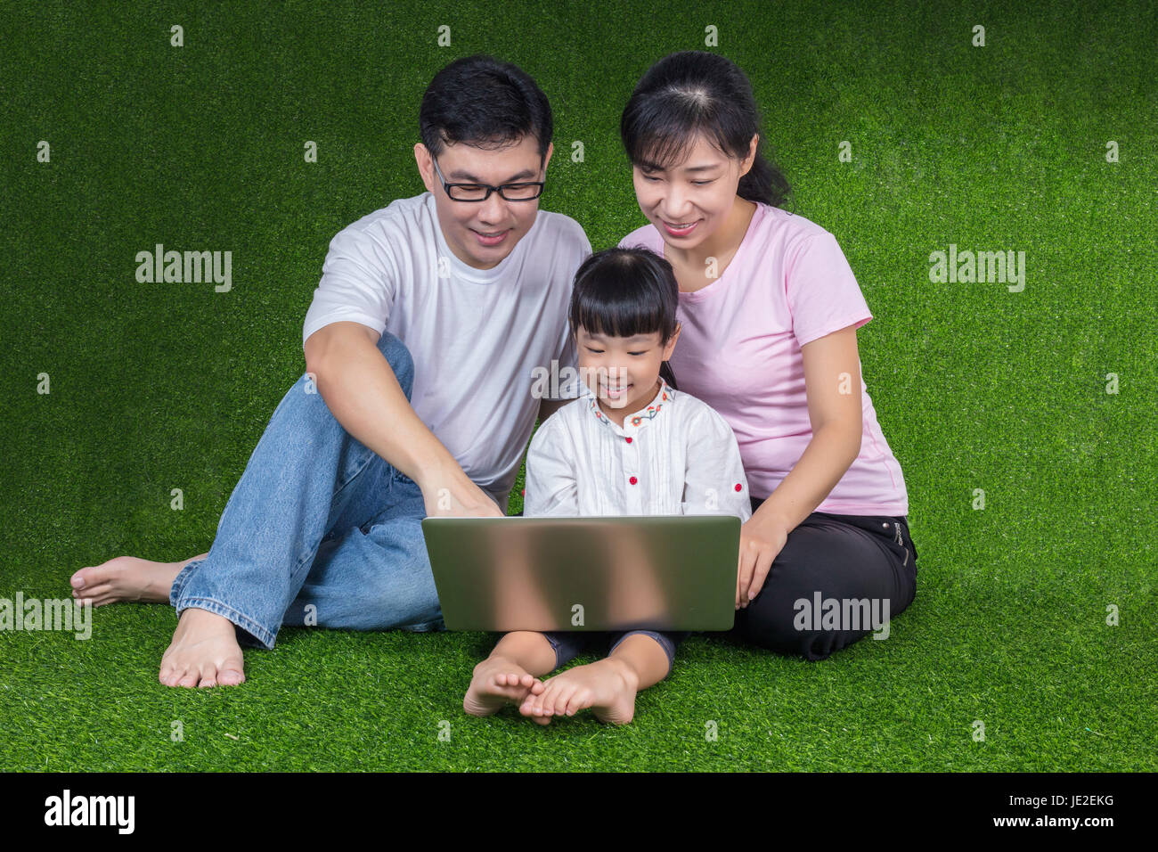 Asian Chinese parents and daughter sitting on the grass and playing ...