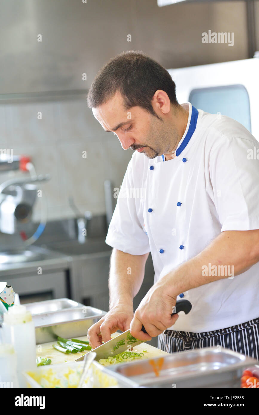 Handsome chef dressed in white uniform decorating pasta salad and ...