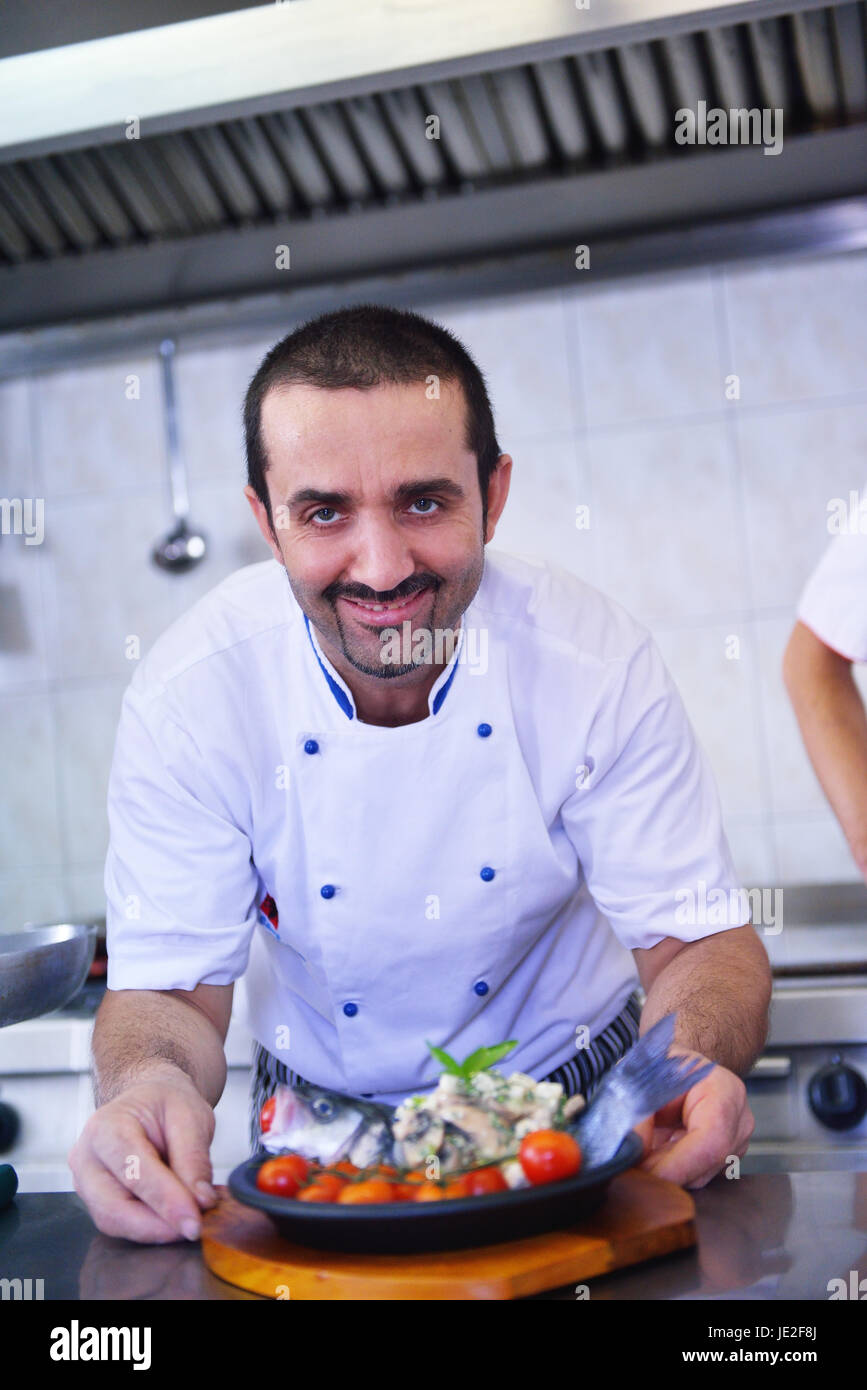 Handsome chef dressed in white uniform decorating pasta salad and ...