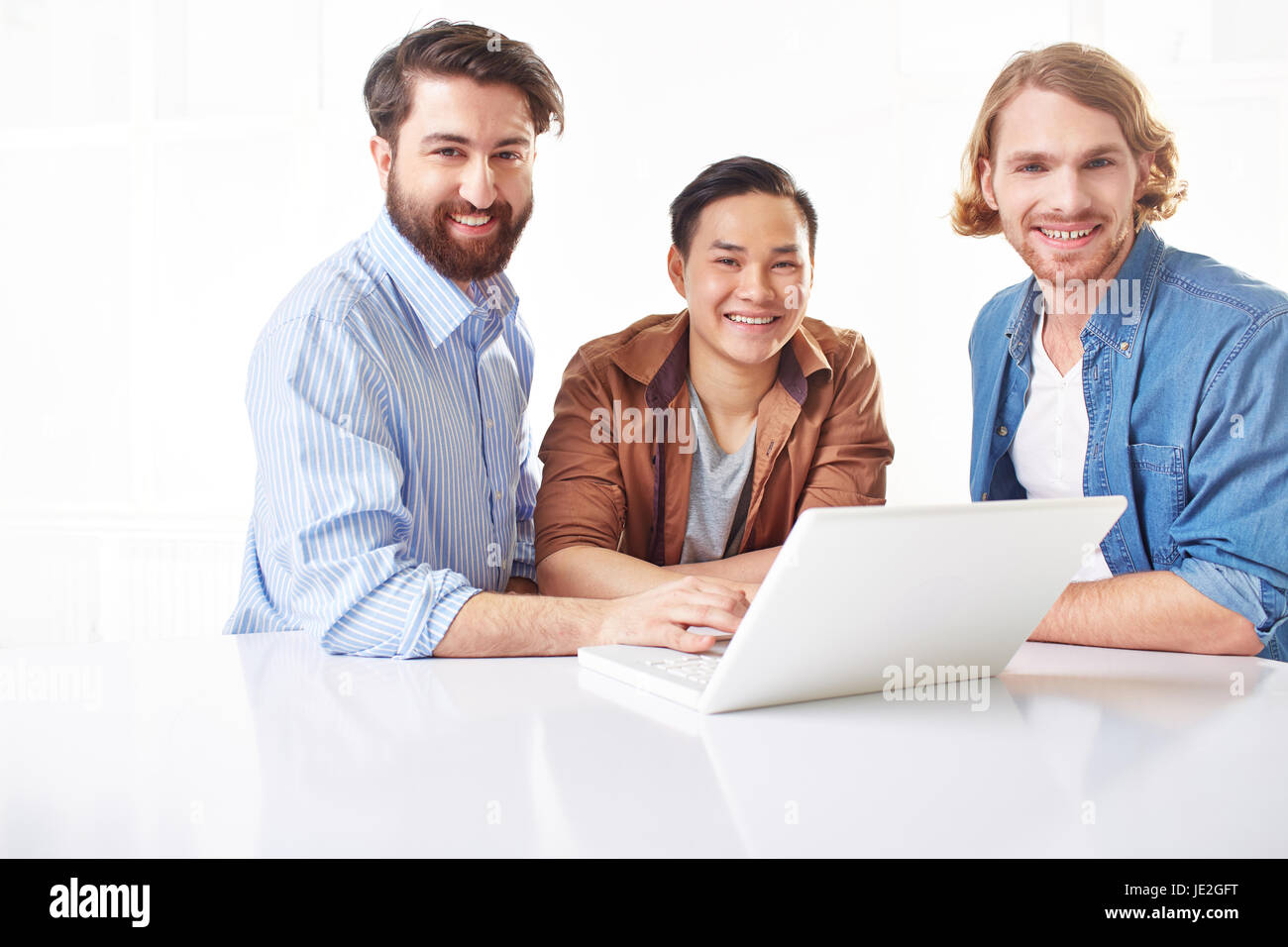 Three handsome young men using a laptop Stock Photo - Alamy